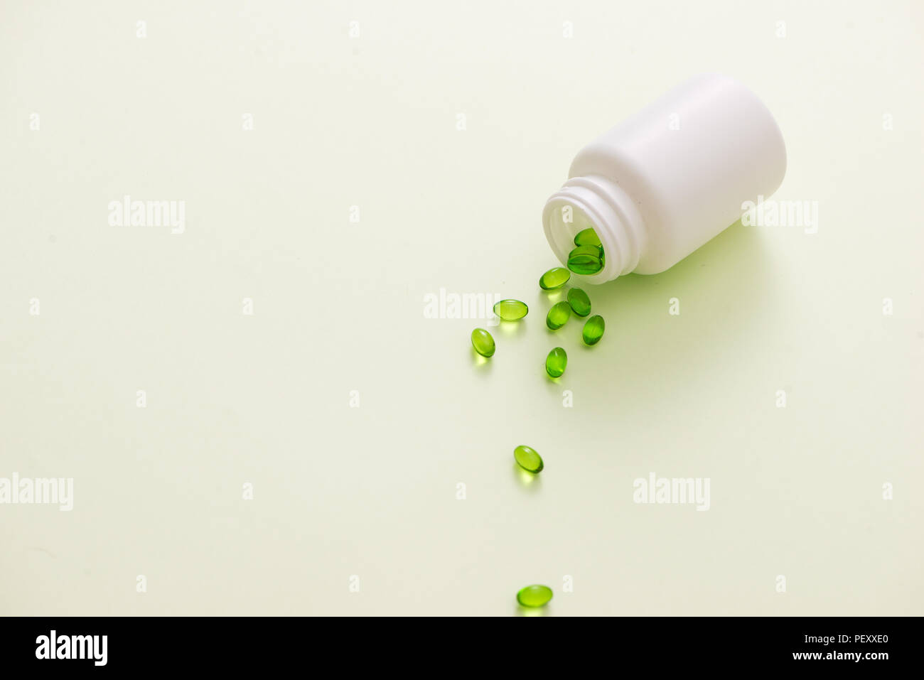 Green capsules in a bottle isolated on white background Stock Photo - Alamy
