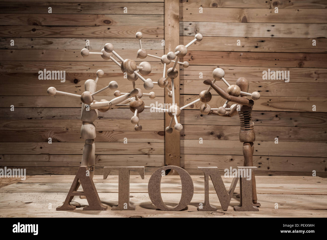 wooden puppets with atom word and atom construction on wood table in ...