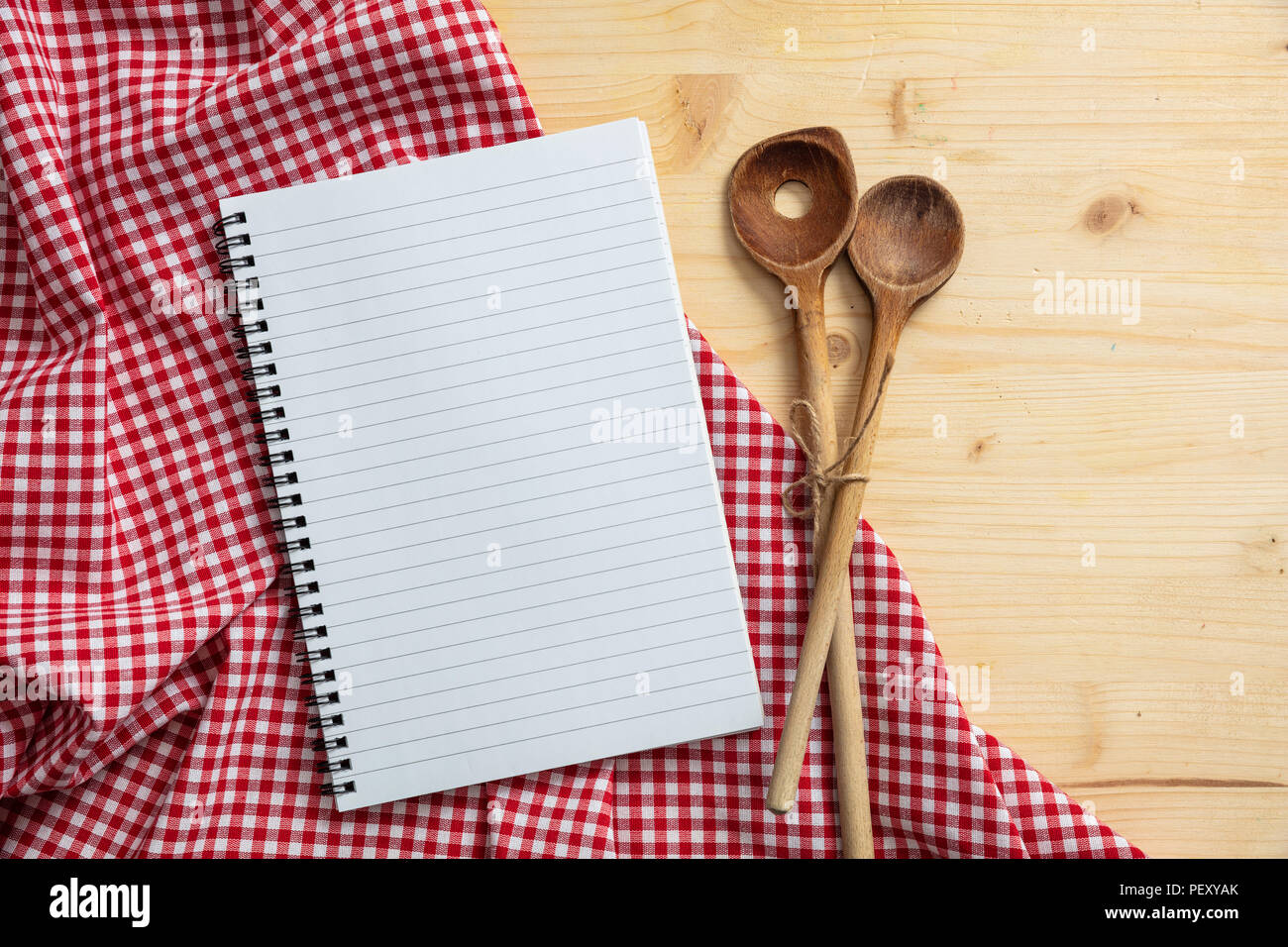 Cooking recipe.Blank notebook, kitchen utensils and red tablecloth on ...