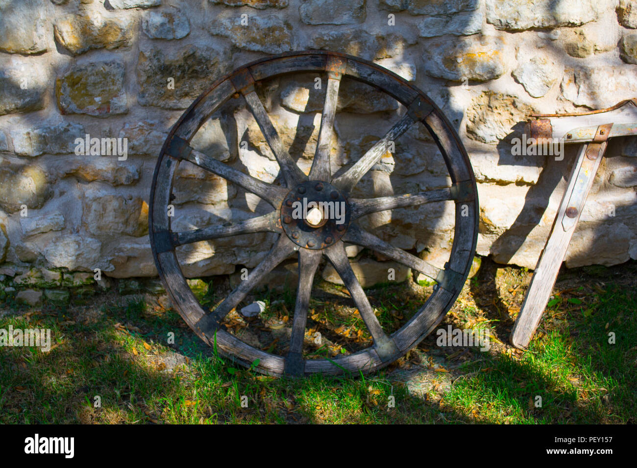 wooden old cartwheel on stone wall background Stock Photo - Alamy