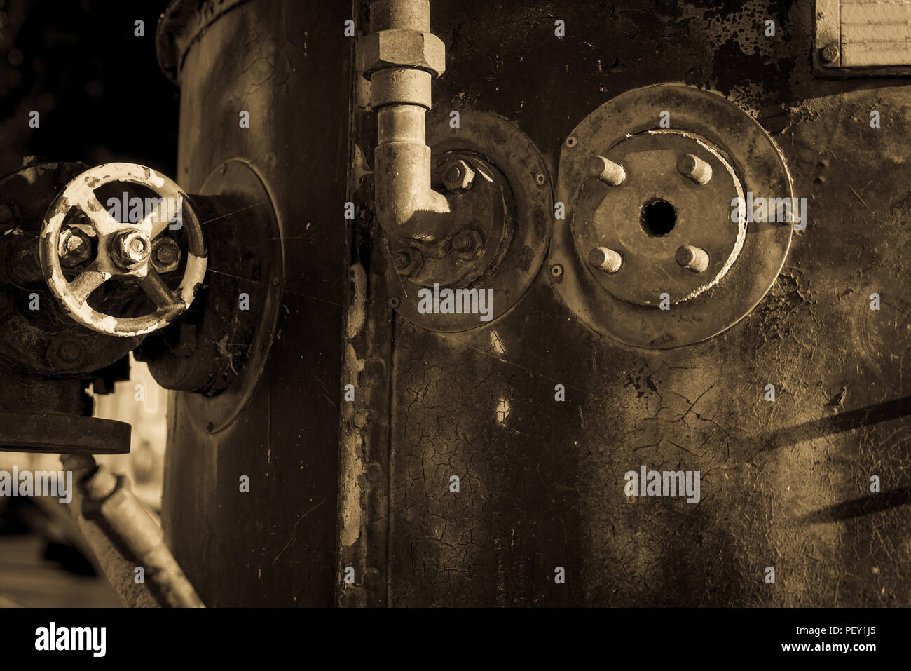 Grungy old steel boiler of steam engine with fittings and valve close ...