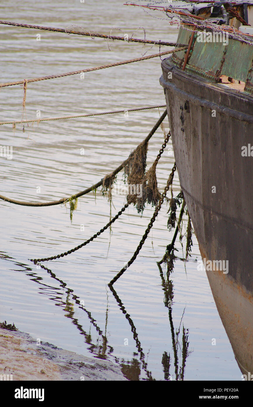 The mooring ropes of a boat reflected in the calm waters of a river ...