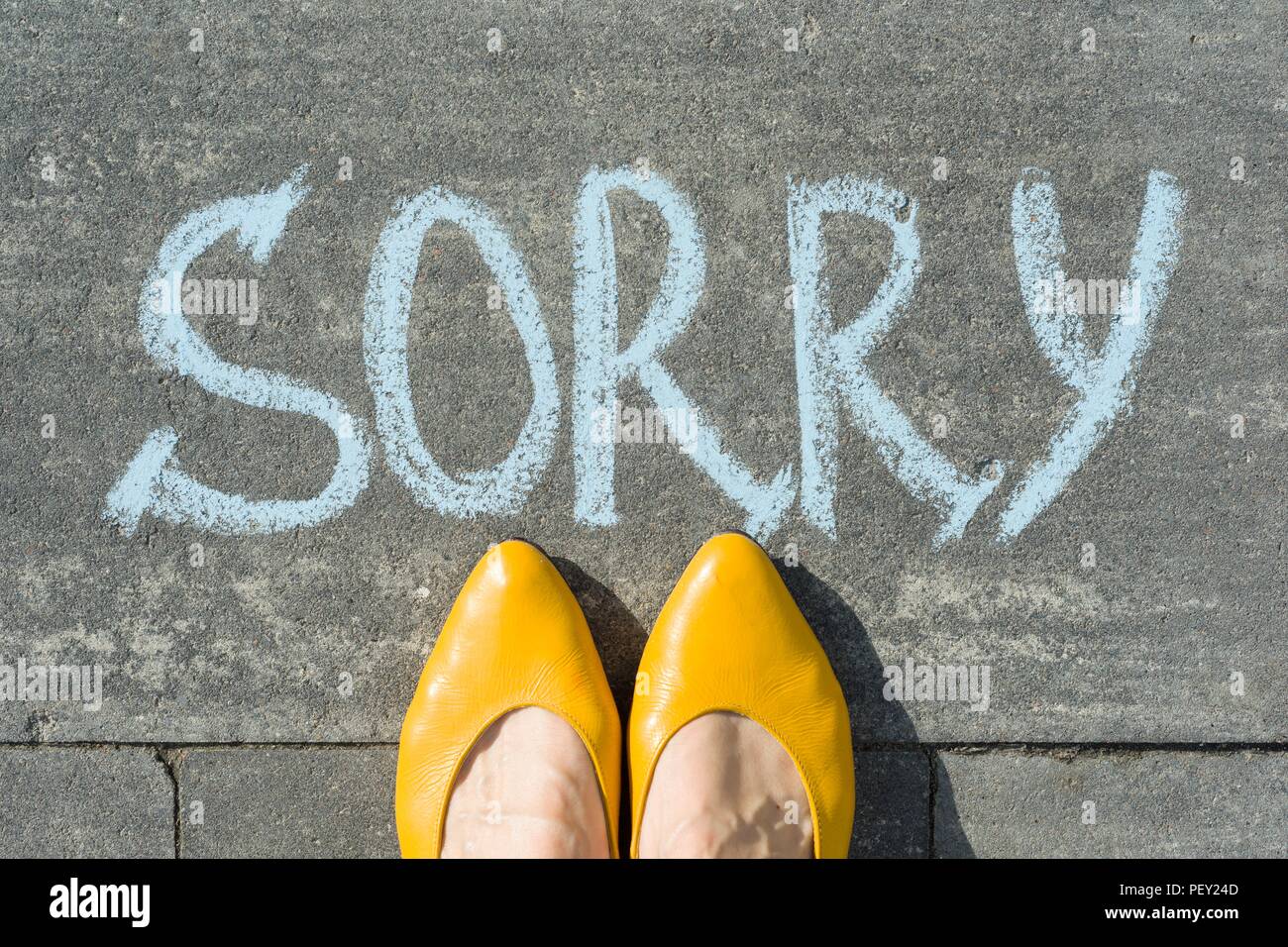 Female feet with text sorry written on Gray asphalt Stock Photo - Alamy