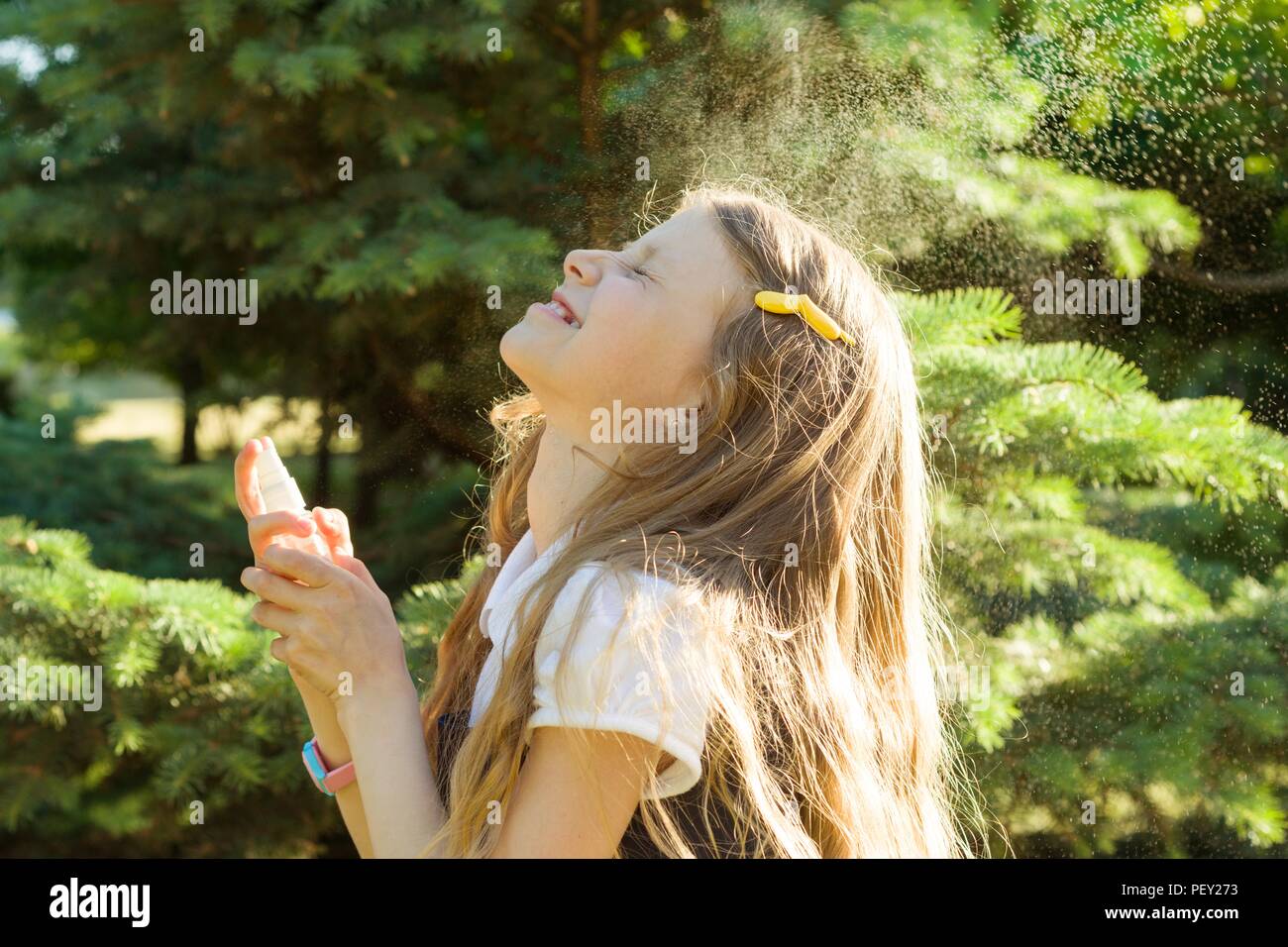 Little girl spraying face with thermal water. Joy and enjoyment on a ...