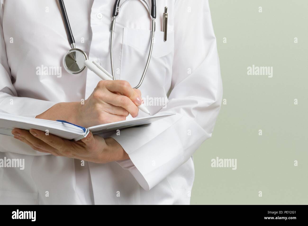 Medical doctor woman with stethoscope taking notes on her notepad ...