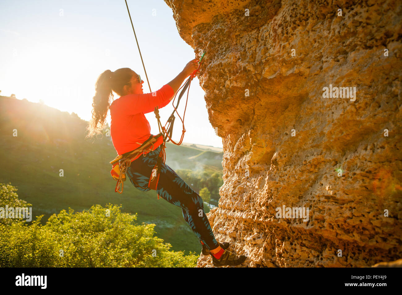 Photo of curly-haired female tourist clambering over rock Stock Photo ...