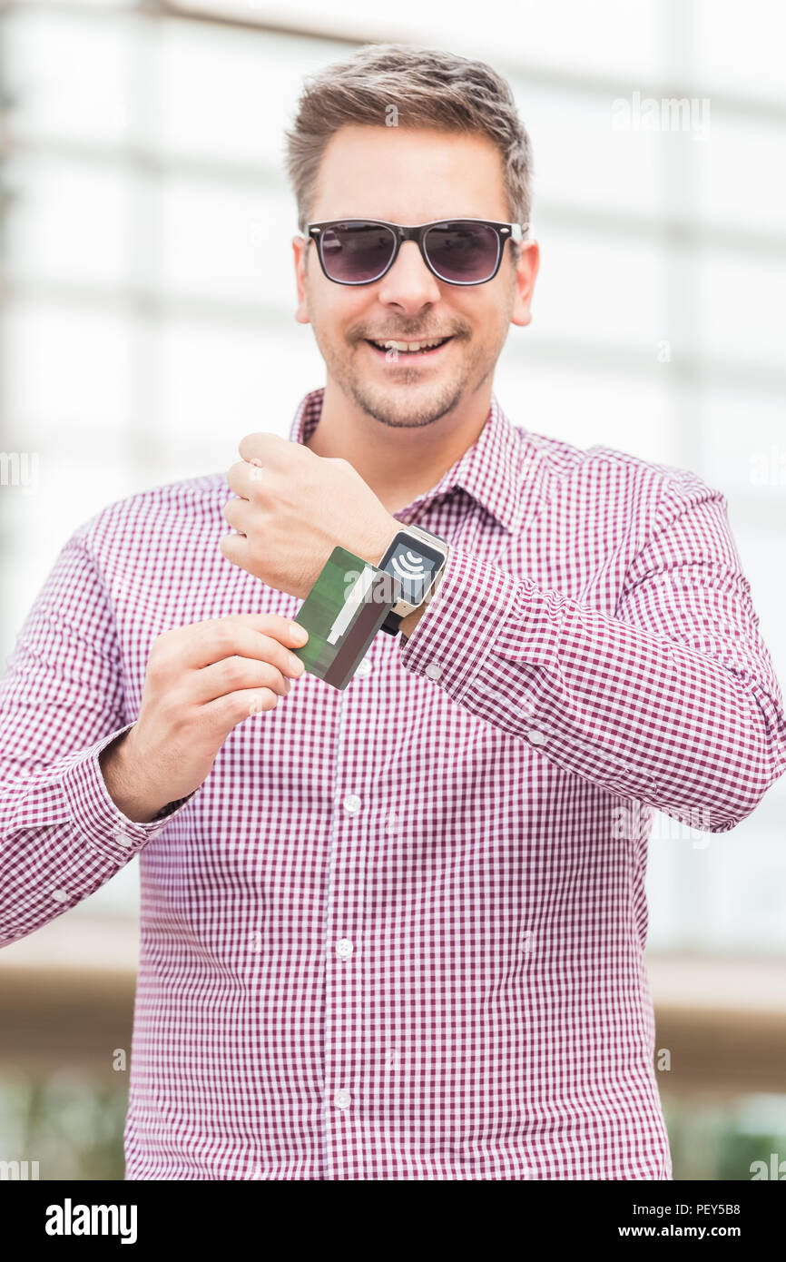 Man making payment by using smartwatch and debit card outdoors Stock ...