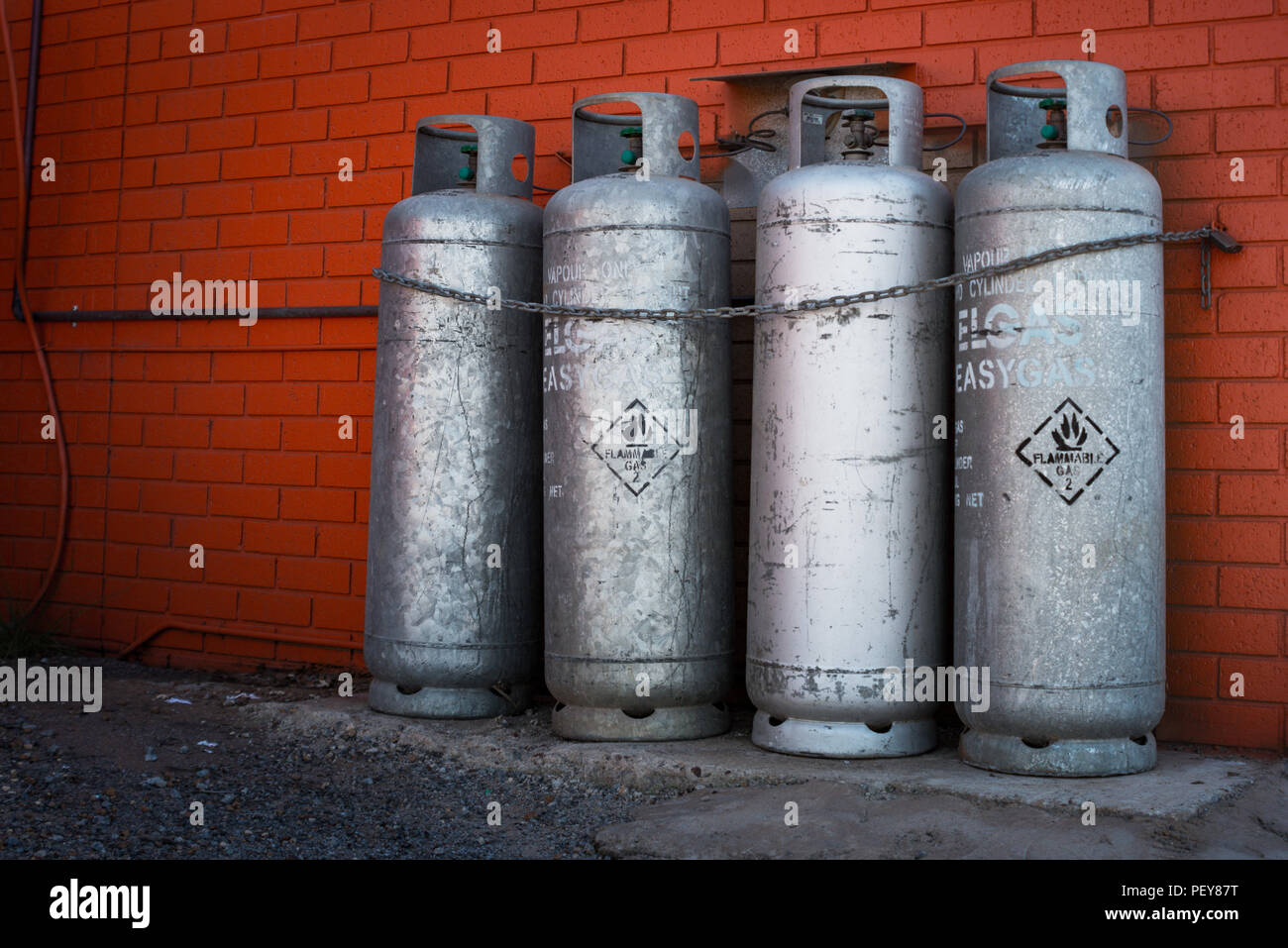 four silver grey gas bottles in front of a red brick wall Stock Photo ...