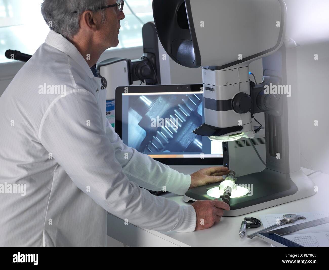 Engineer using a stereo microscope to inspect a manufactured component ...