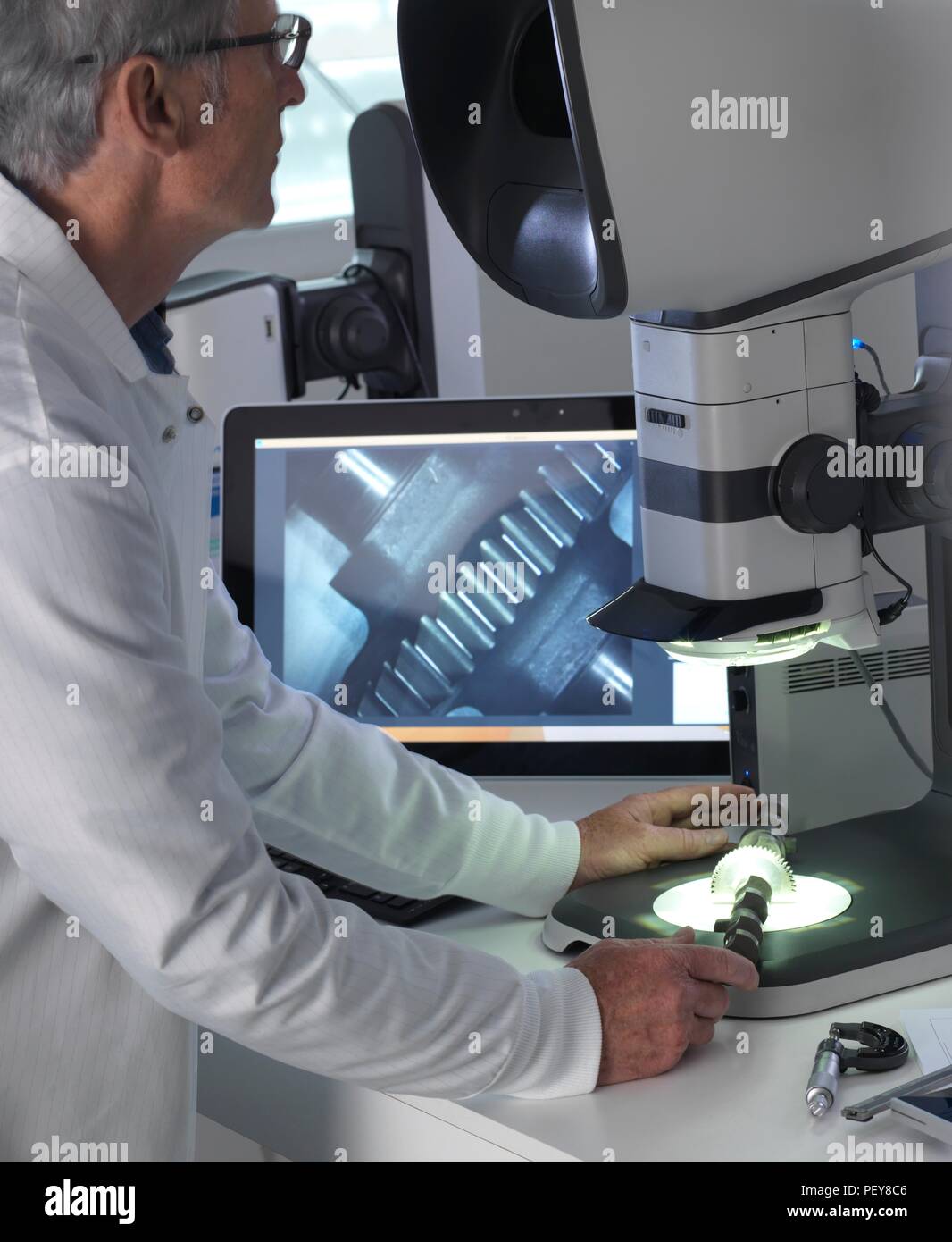 Engineer Using A Stereo Microscope To Inspect A Manufactured Component