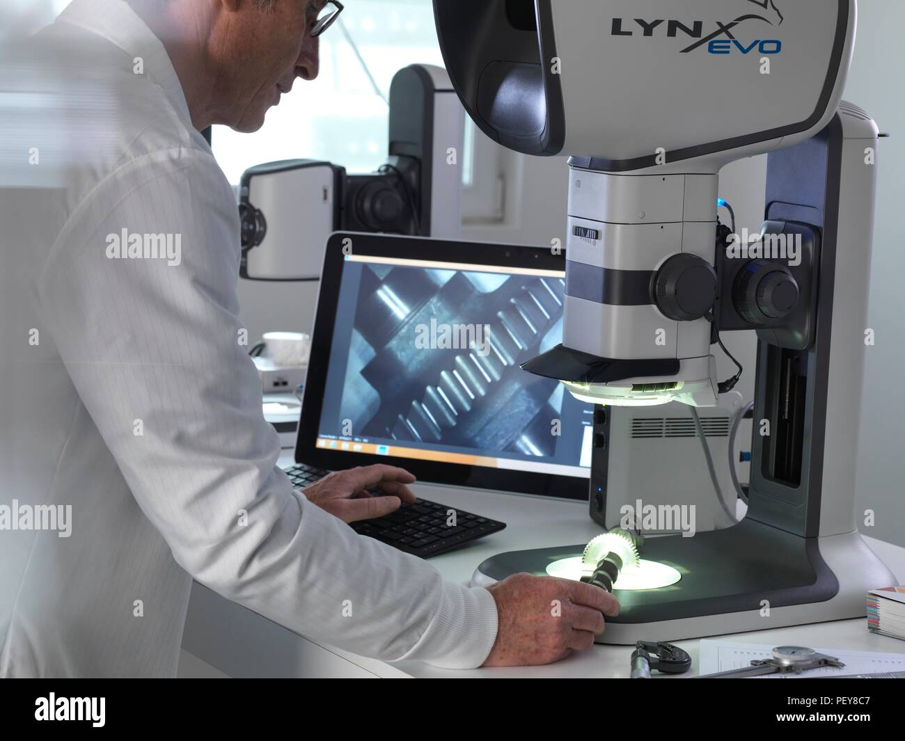 Engineer using a stereo microscope to inspect a manufactured component ...