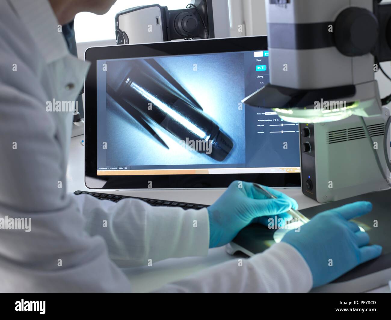 Forensic scientist using a 3d stereo microscope to view markings on a ...