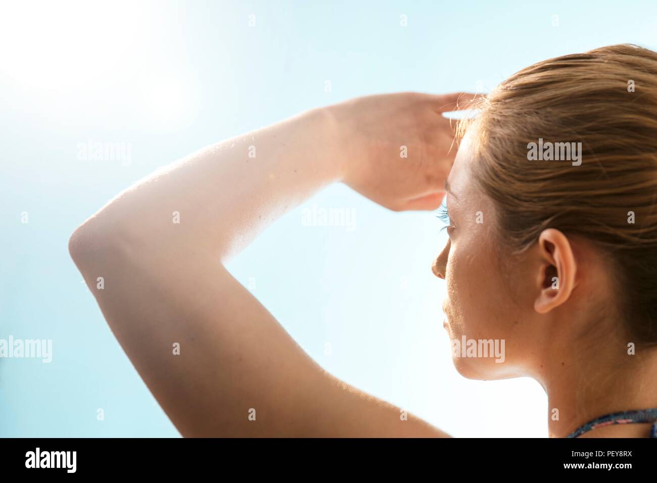 Woman shielding her eyes from the sun Stock Photo - Alamy