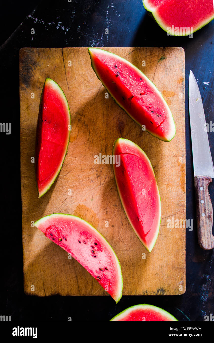 Watermelon cut on a wooden cutter over a black bord, top view, low key ...