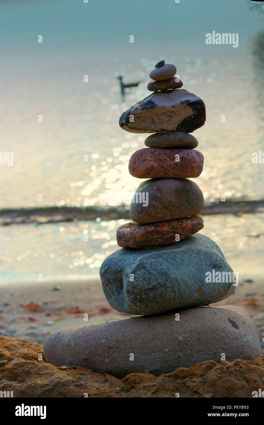Stones stacked on top of each other on the beach with sea view in the ...