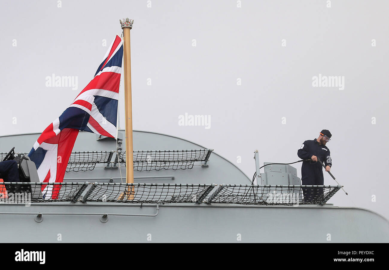 A Royal Navy rating jet washes the deck of HMS Queen Elizabeth, as ...
