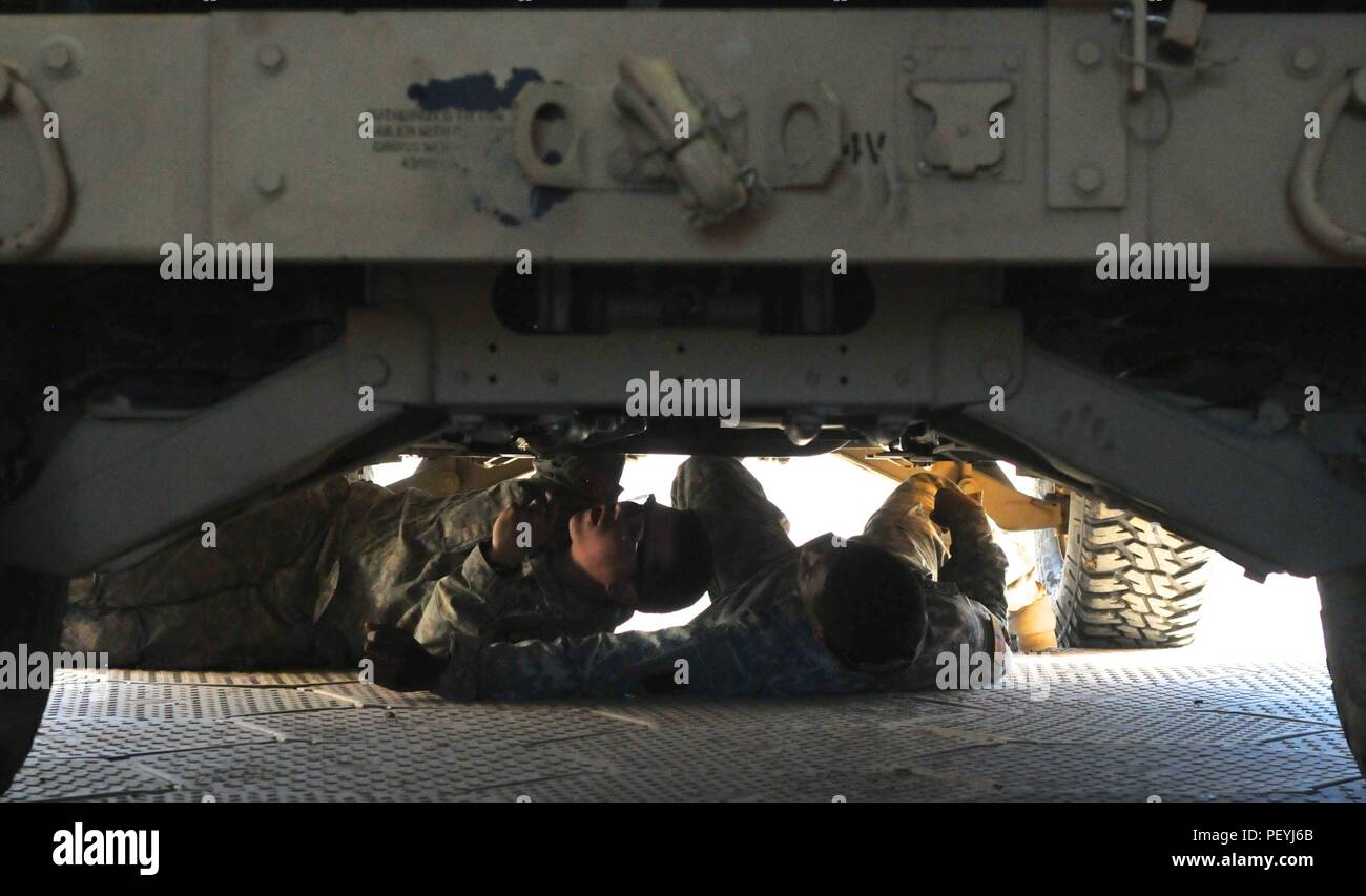Army mechanics work on the underbelly of a Humvee in the maintenance ...