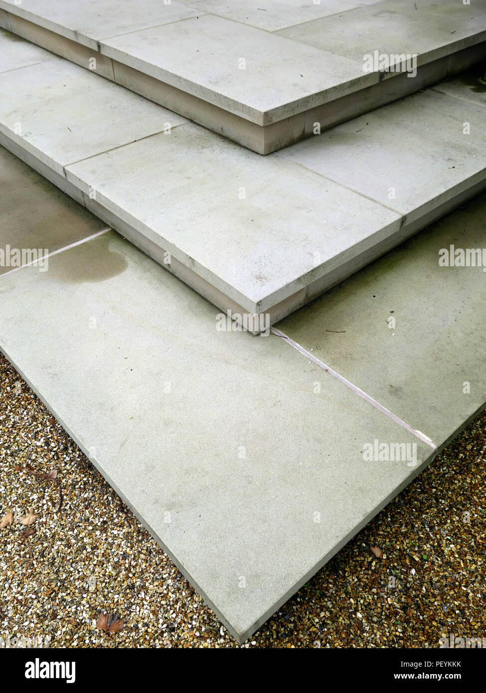 Modern stone slabs forming pathways around a formal garden area of an ...