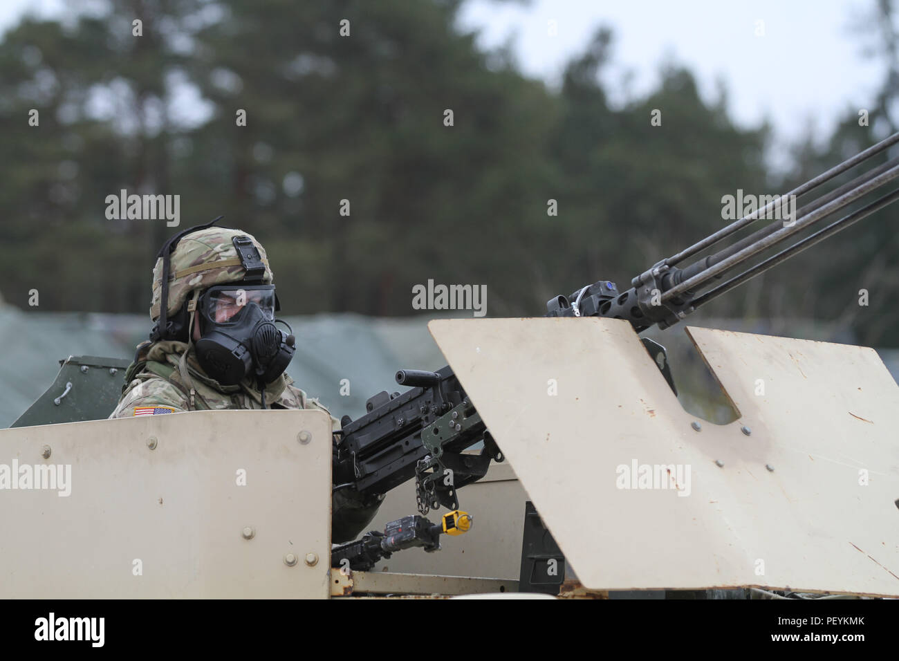 Wearing a protective mask, a gunner aboard a U.S. Army M1126 Stryker ...