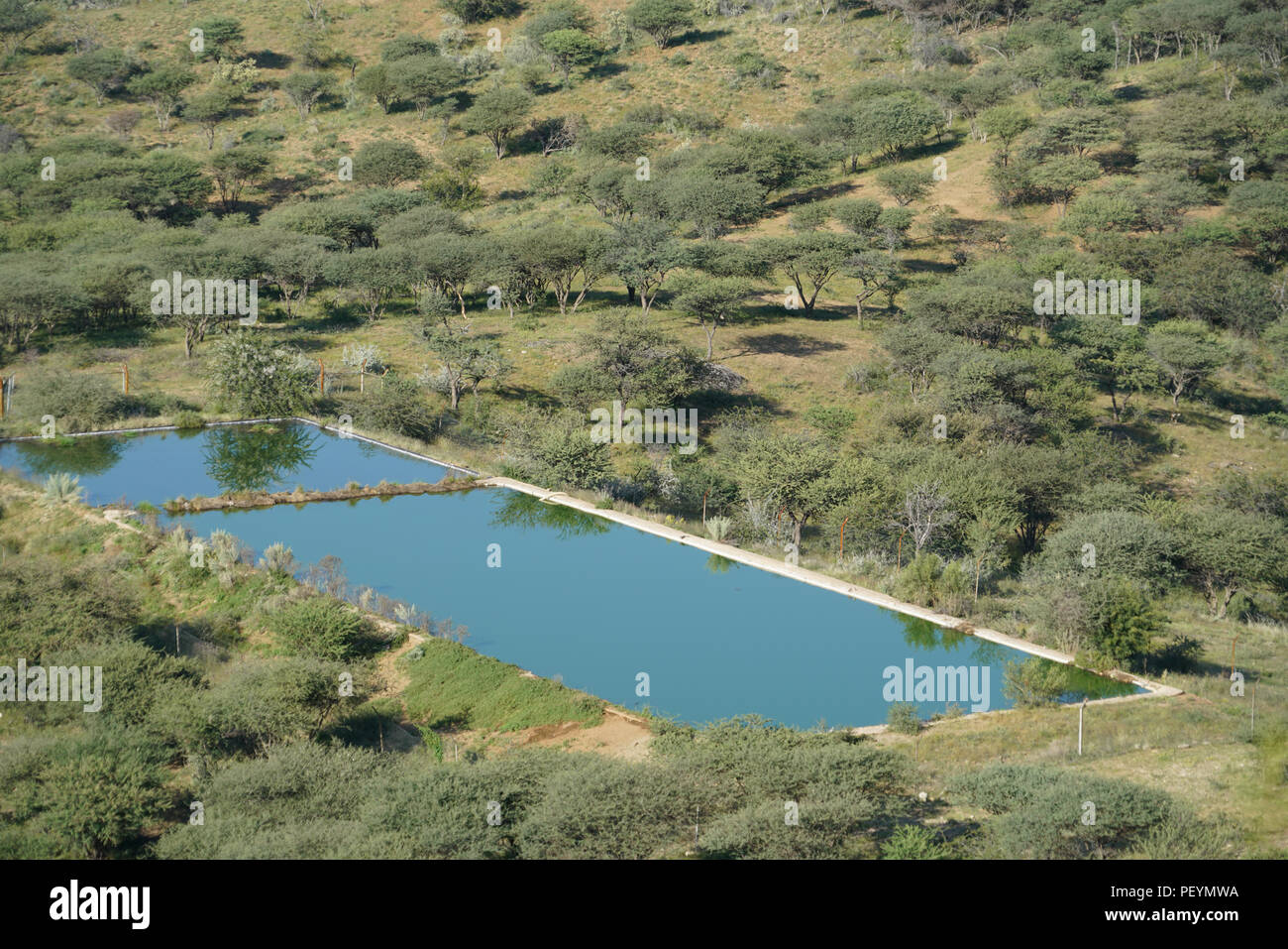 Turquoise still water in reservoir surrounded by landscape scattered ...