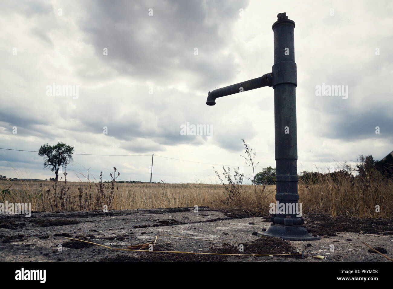 Old pump with dry soil, dramatic cloudy sky, water shortage Stock Photo - Alamy