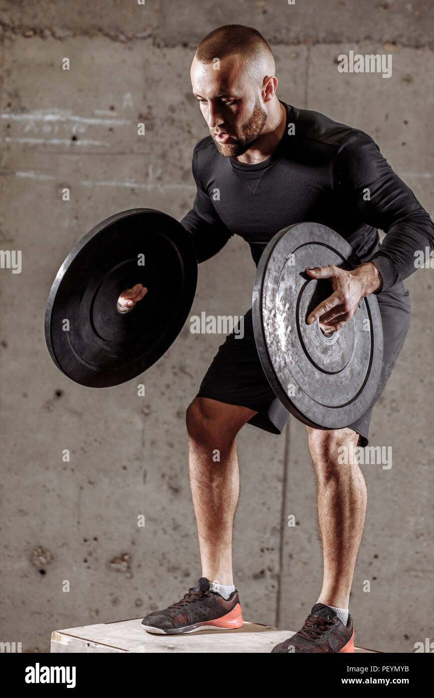 bearded handsome ginger fit man doing hard exercises with weight plate ...