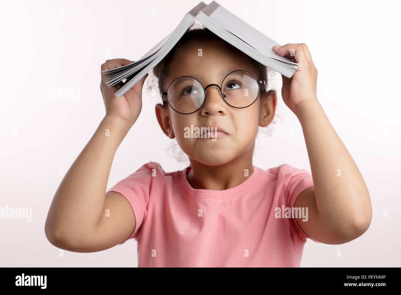 african funny girl with a book is looking up and making faces. closeup ...