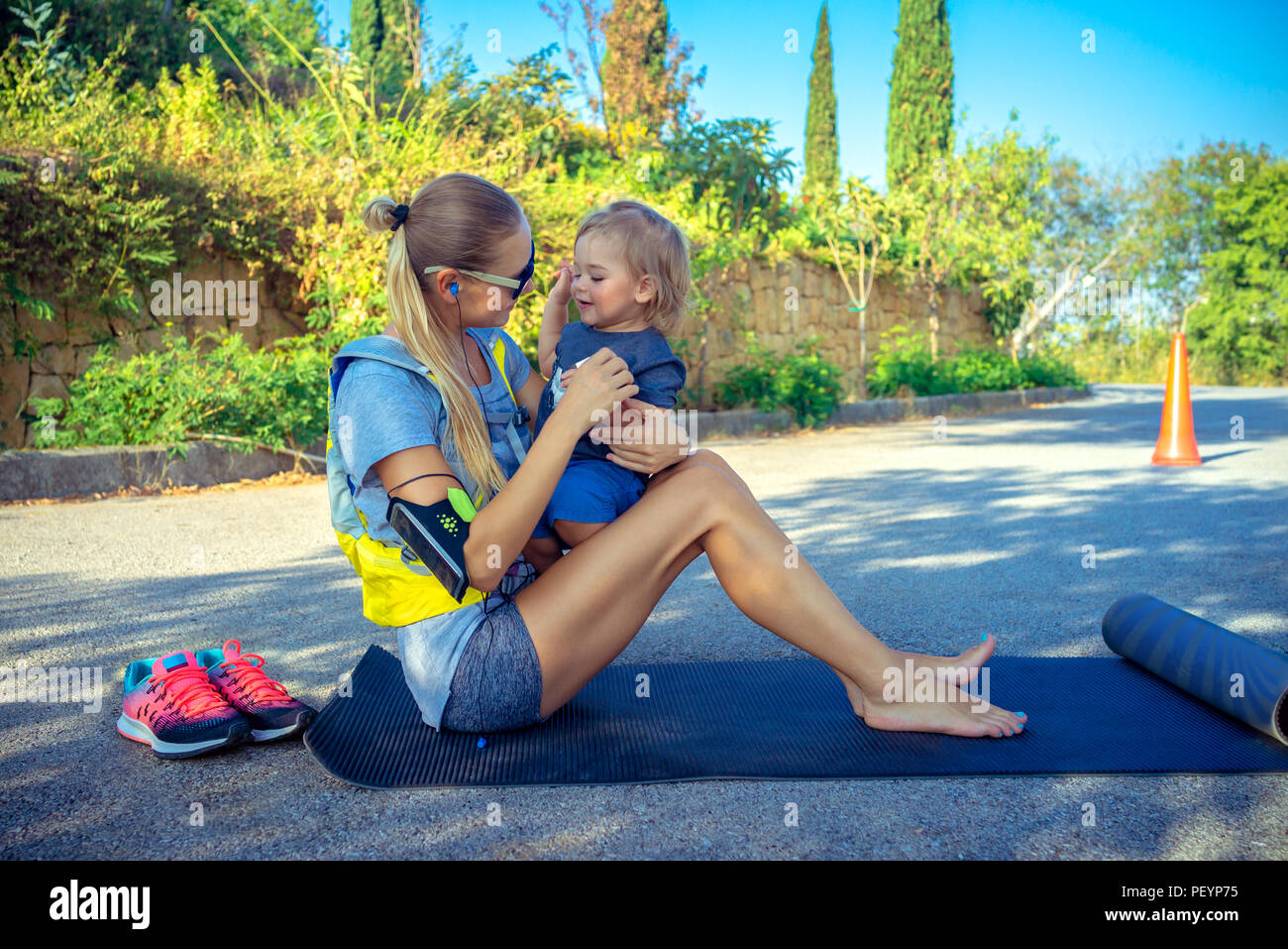 Mother with baby doing exercise outdoors in the park in bright sunny ...