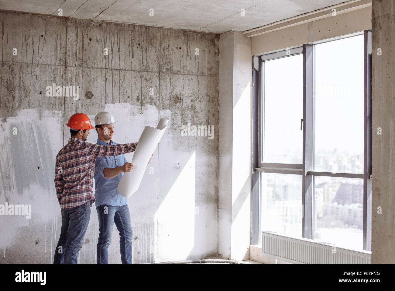 building company. handsome engineer is showing a construction plan to ...