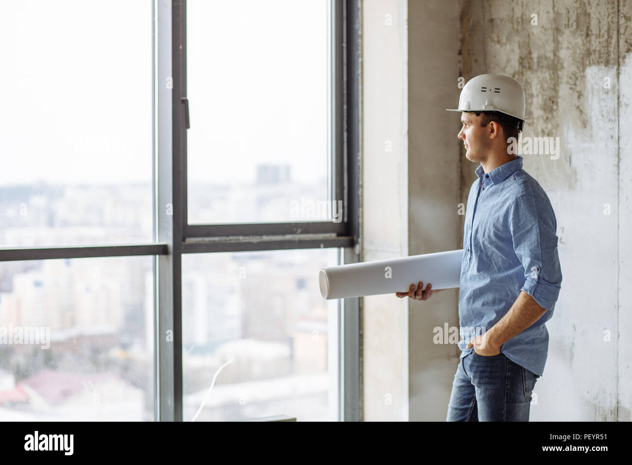 handsome guy in hardhat putting his hand on the pocket and looking at ...