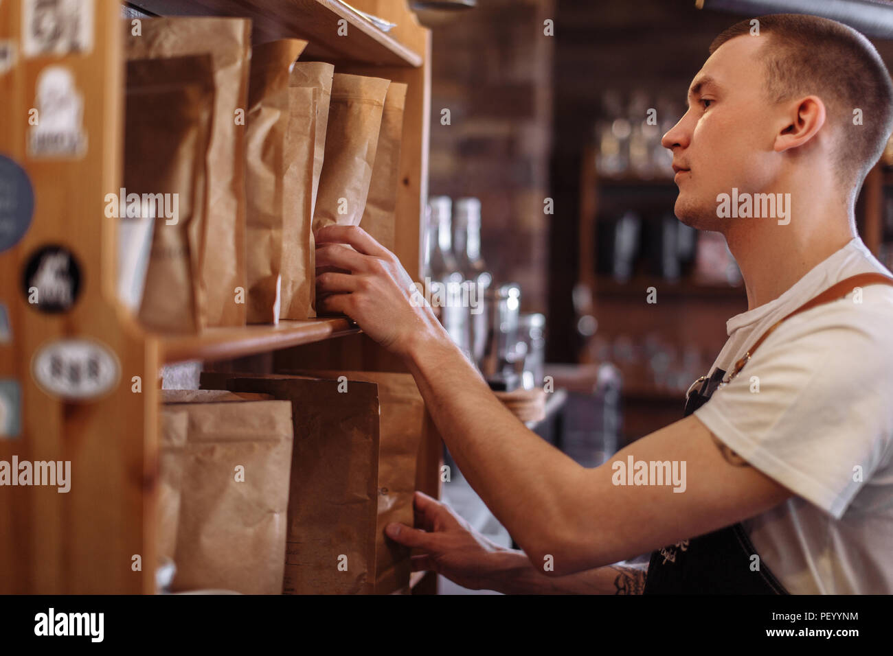 a pleasant man in an apron is taking the parcel from the shelf Stock ...