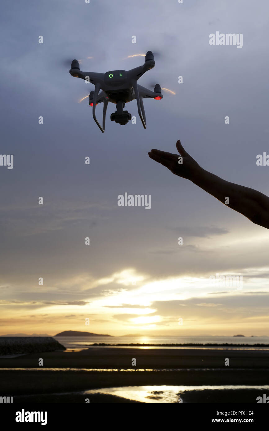 Hand catching drone aircraft in sunset sky background, camera operator ...