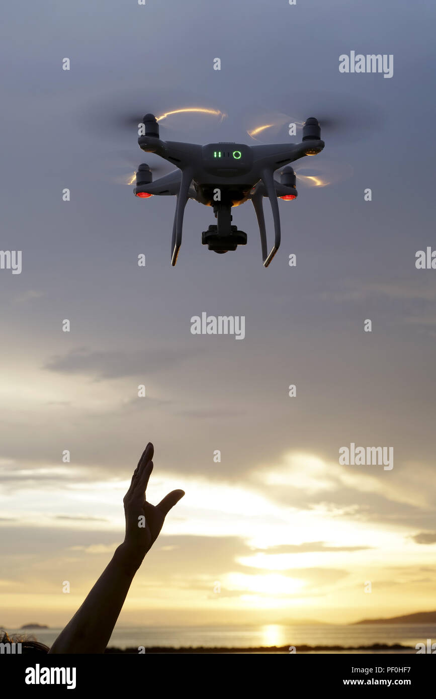 Hand catching drone aircraft in sunset sky background, camera operator ...