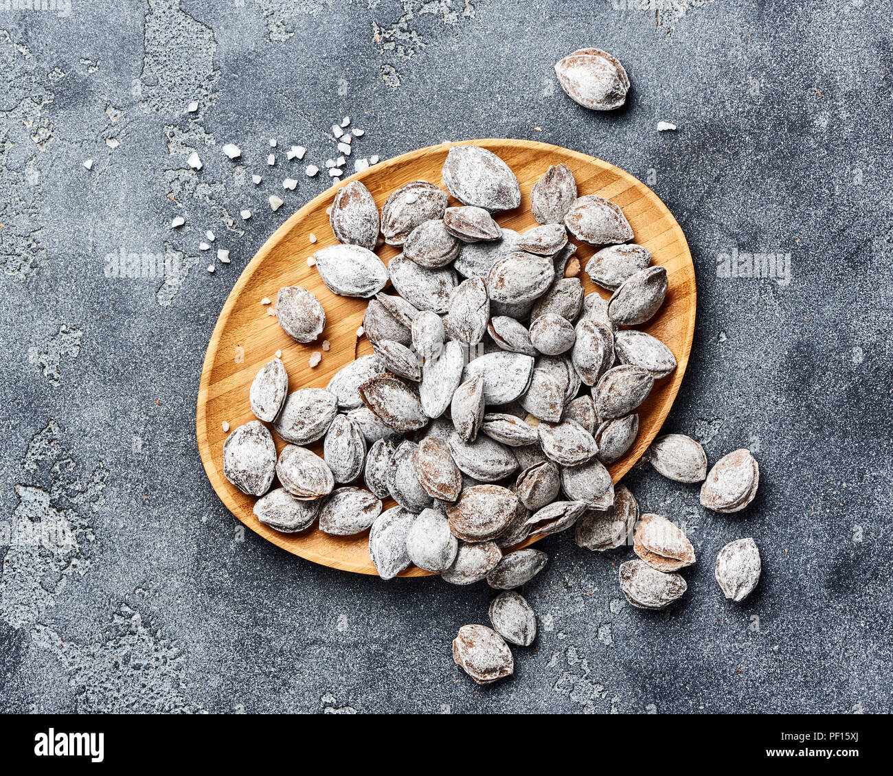 Salted apricot seeds on grey background. Apricot bones fried with salt ...