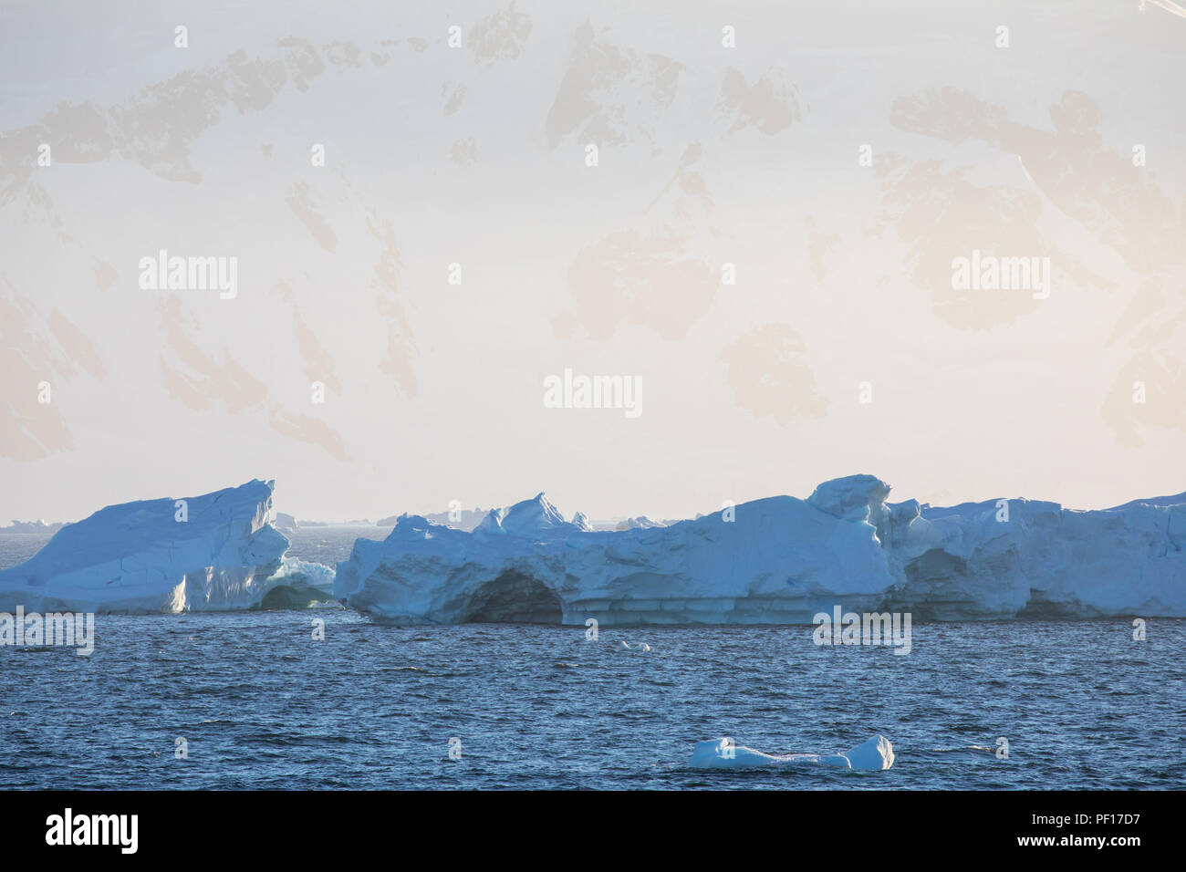 icecaps in the Antarctica with iceberg in the ocean swimming around and ...