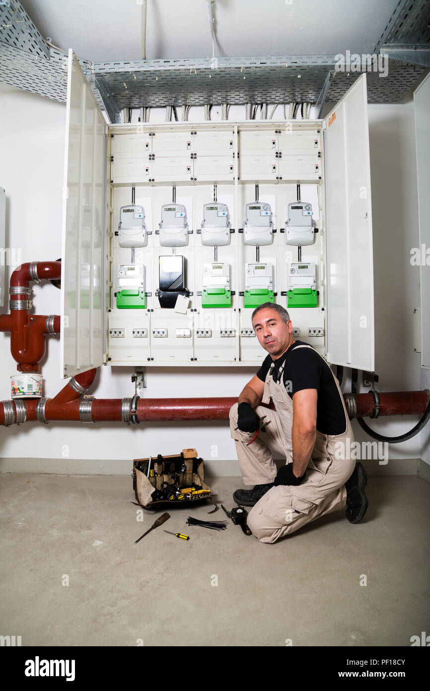 Electrician with box of tools seating near distribution board Stock ...