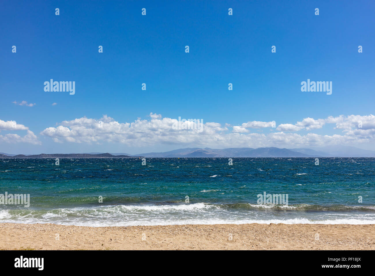 Windy sandy beach, rough sea with waves, blue sky with clouds ...
