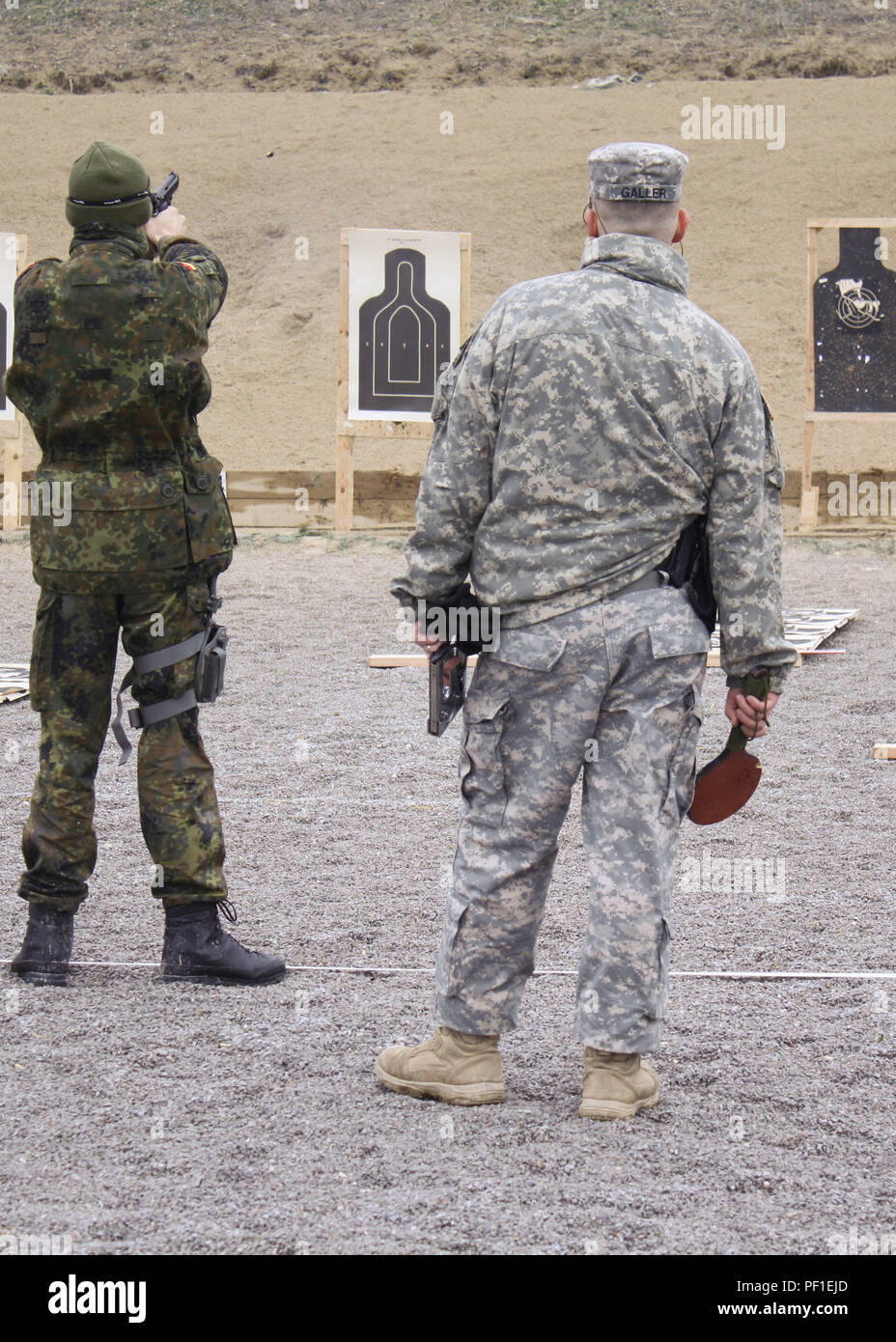 German Army Maj. Falk Grundshok fires an M9 pistol while U.S. Army Sgt ...