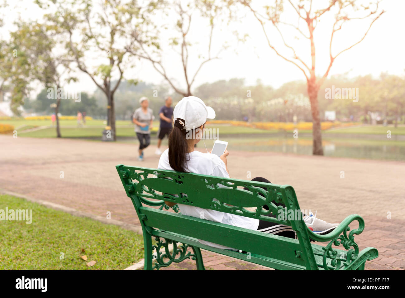 Woman sit on a bench relaxing using cell phone Stock Photo - Alamy