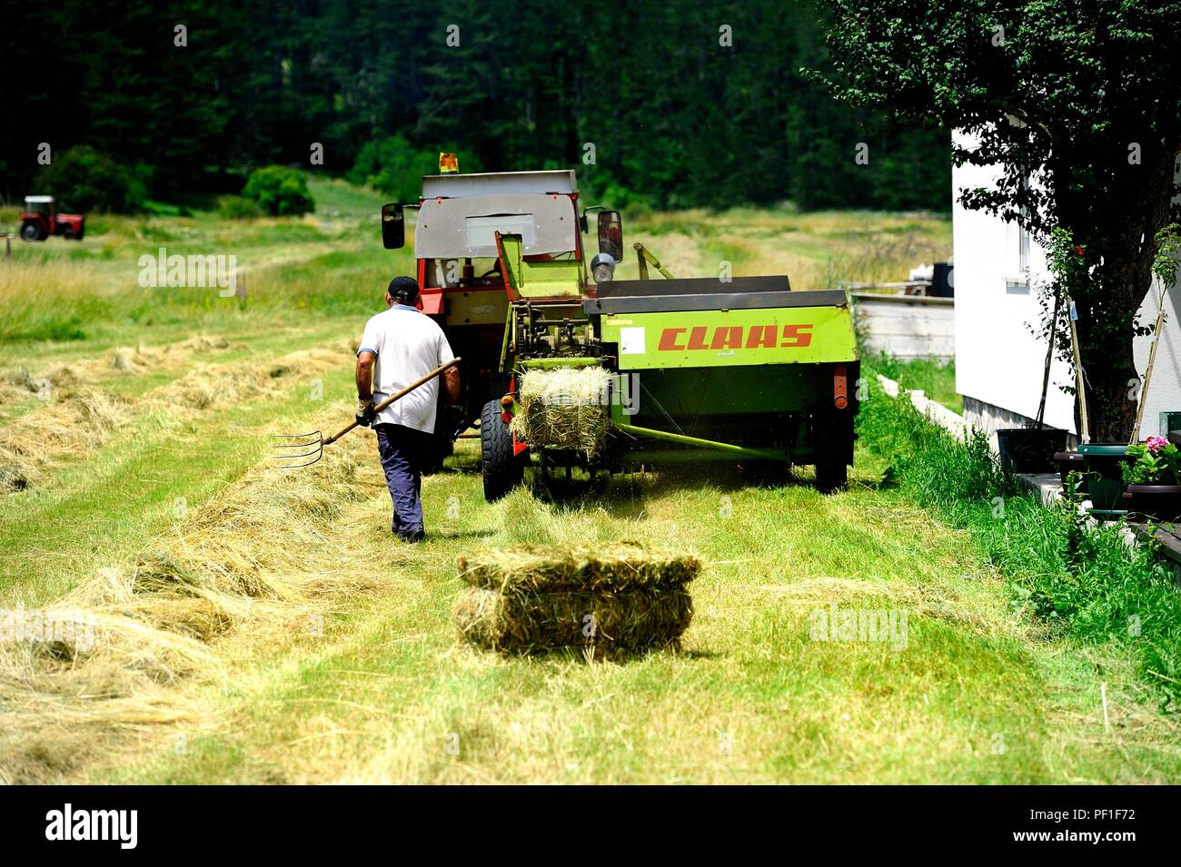 Farmer supervising the baling machine Stock Photo - Alamy
