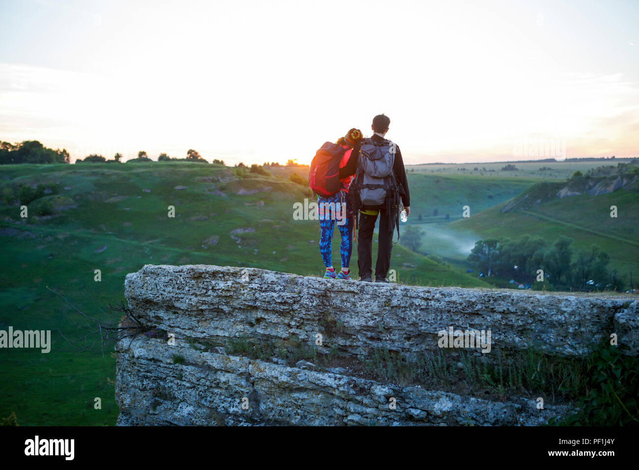 Photo from back of hugging man and tourist woman with backpacks on ...