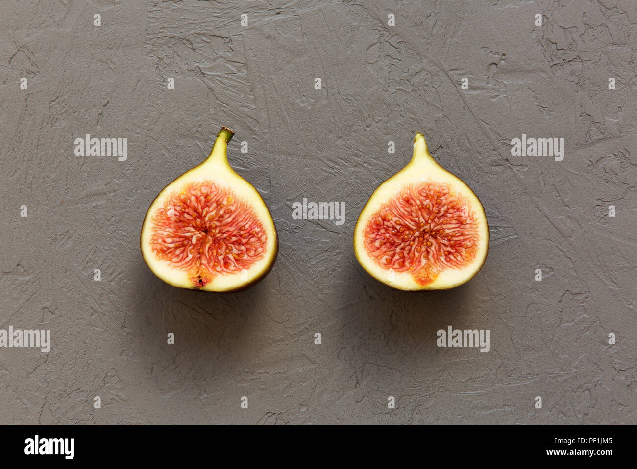 Two halves of a fig on concrete background, top view. Overhead, from ...