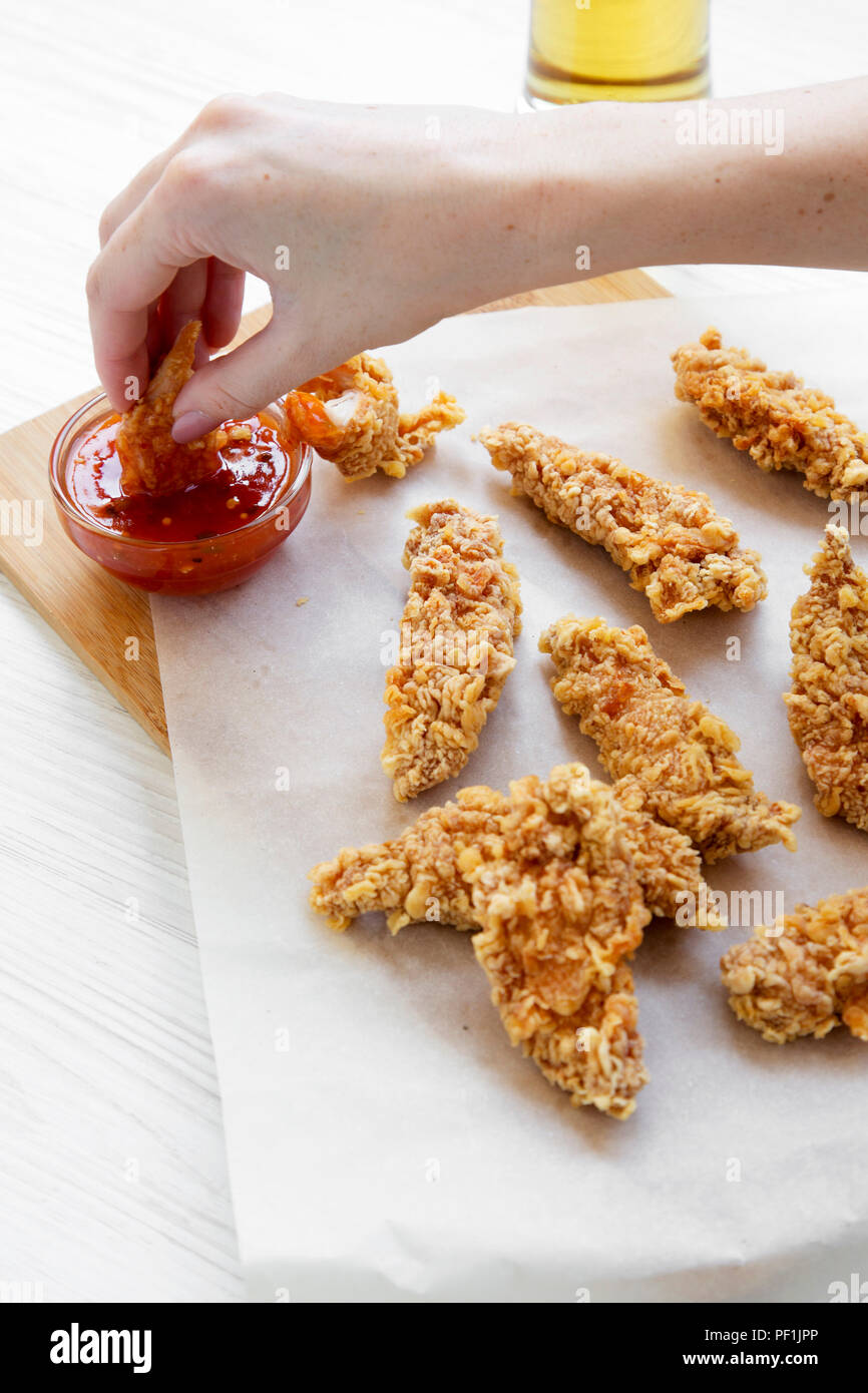 Female hand dipping chicken strips into sauce, close-up Stock Photo - Alamy