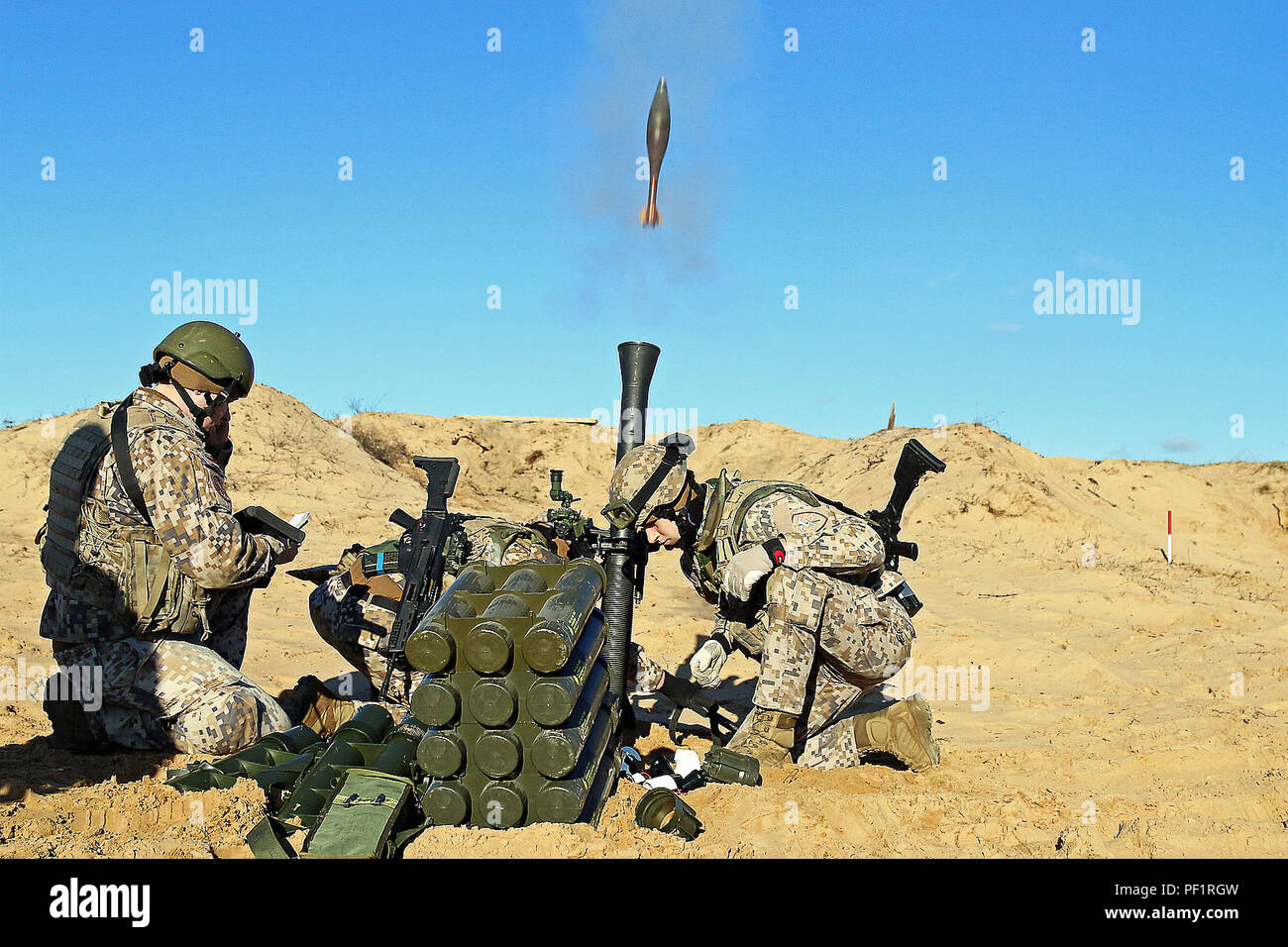 Latvian soldiers fire an 81mm mortar round from an M252 mortar system ...