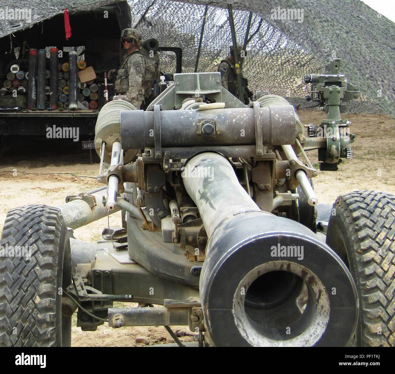 A 119A2 howitzer cannon is positioned in a camouflaged artillery ...