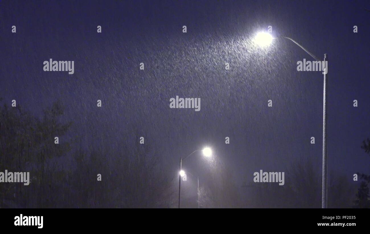 Snow falls against the background of a lamppost at night. Night winter ...