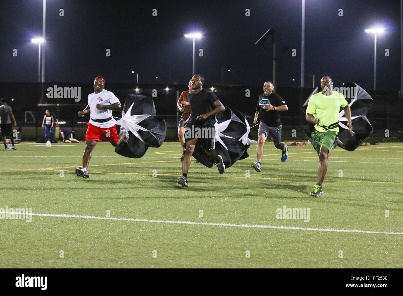 A group of friends sprint with parachutes on their backs during a ...
