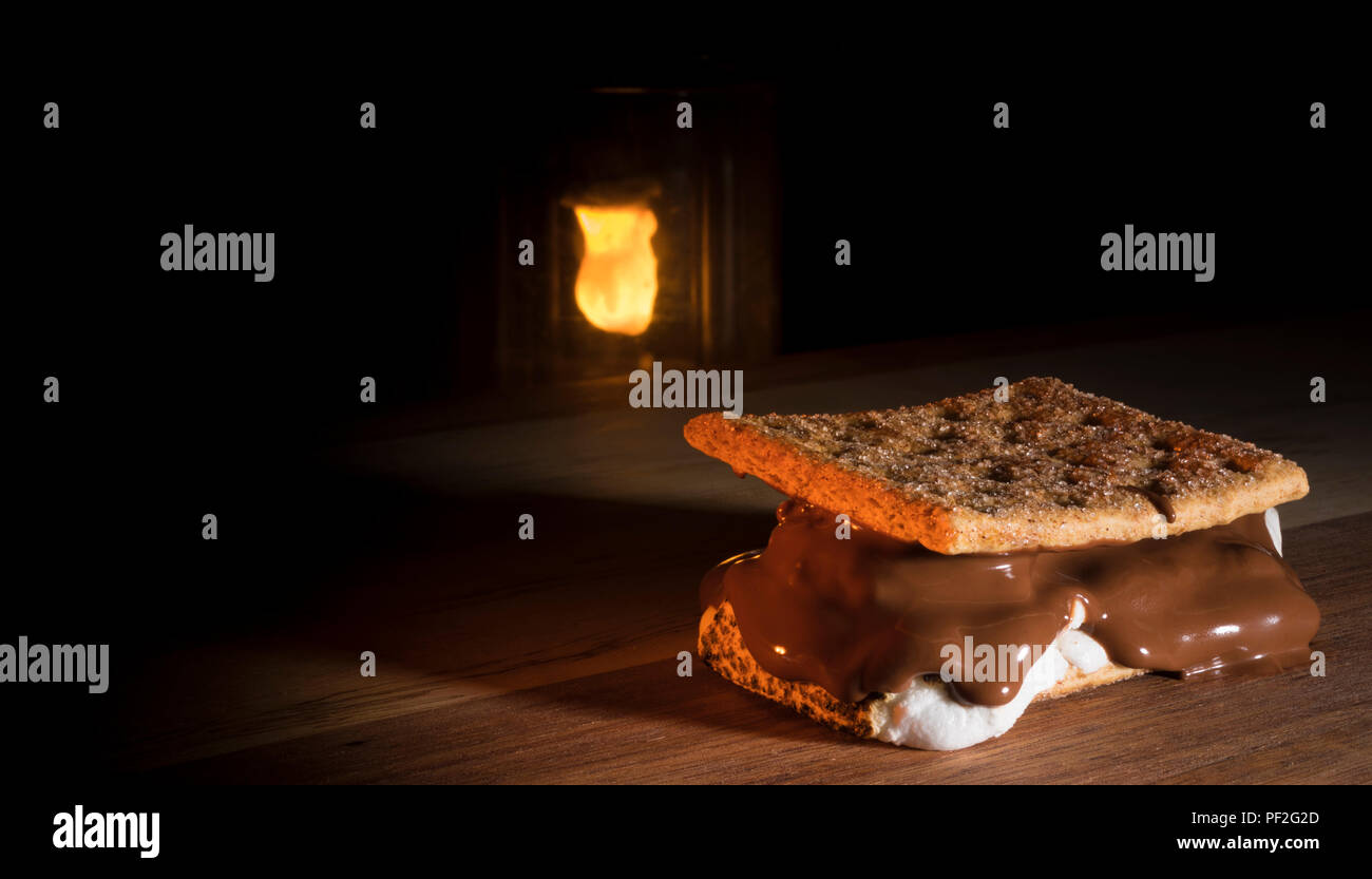 Camping lantern lit behind a wood table with a smore on top Stock Photo ...