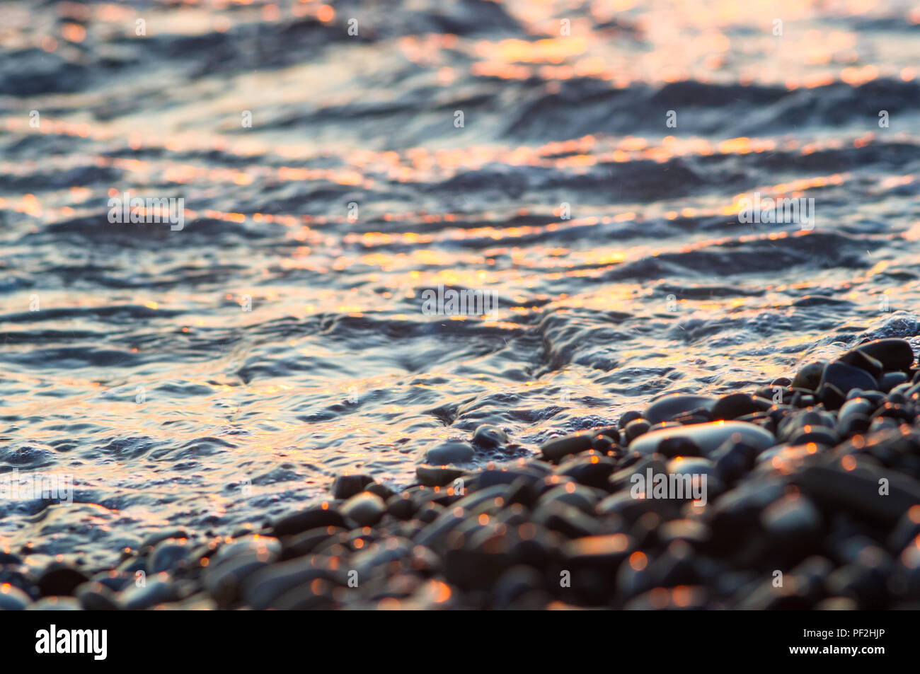 pebble stones on the sea beach on a warm summer day, the rolling waves ...