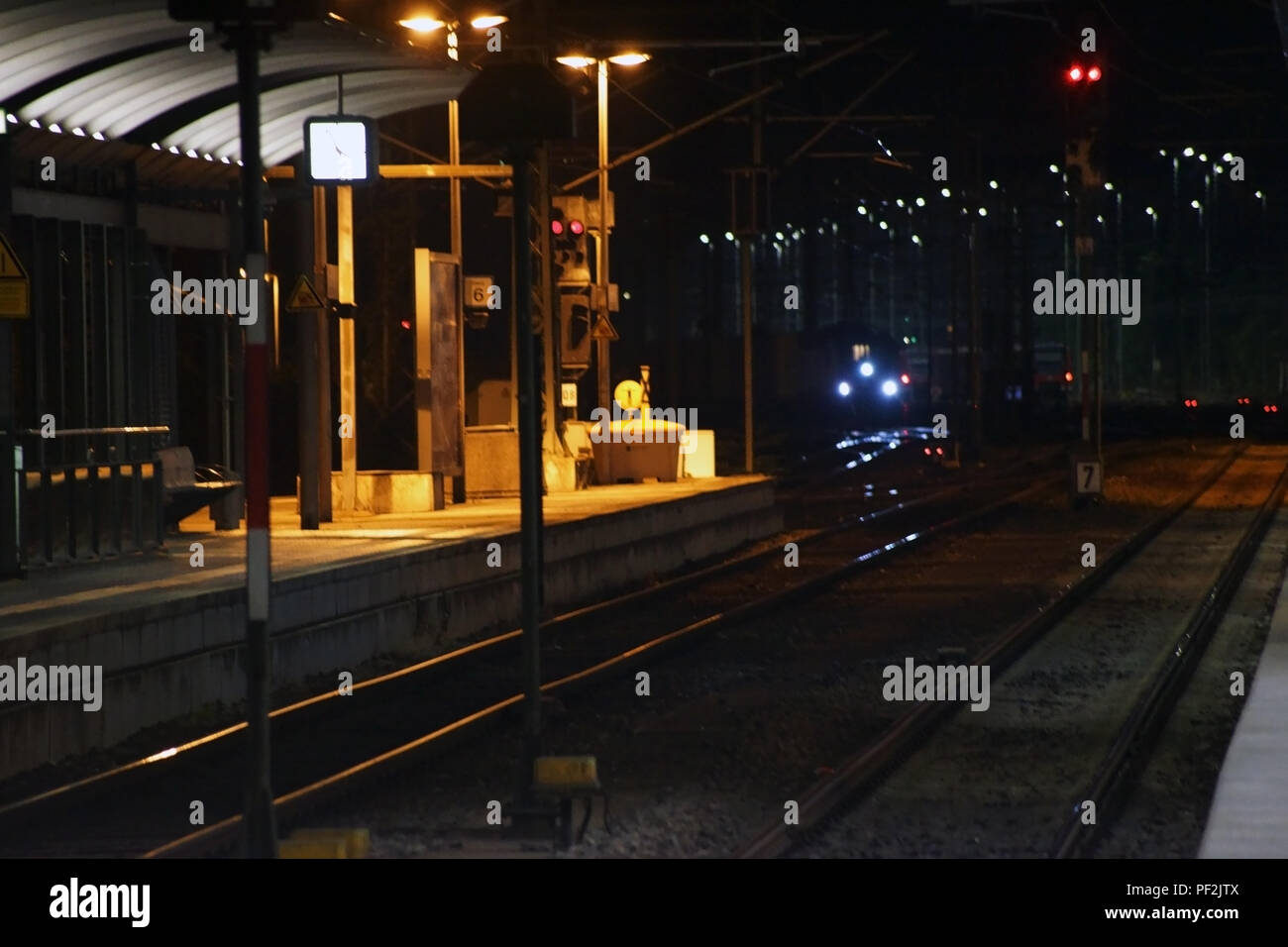 The platform of a railway station at night with an incoming train in ...